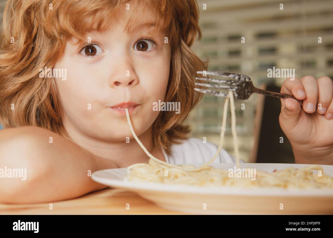 Funny child eating pasta, spaghetti, face close up. Kids head portrait ...