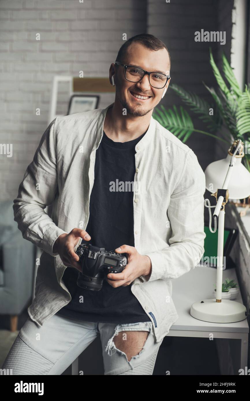 Man standing with digital camera smiling looking at camera. ashion ...