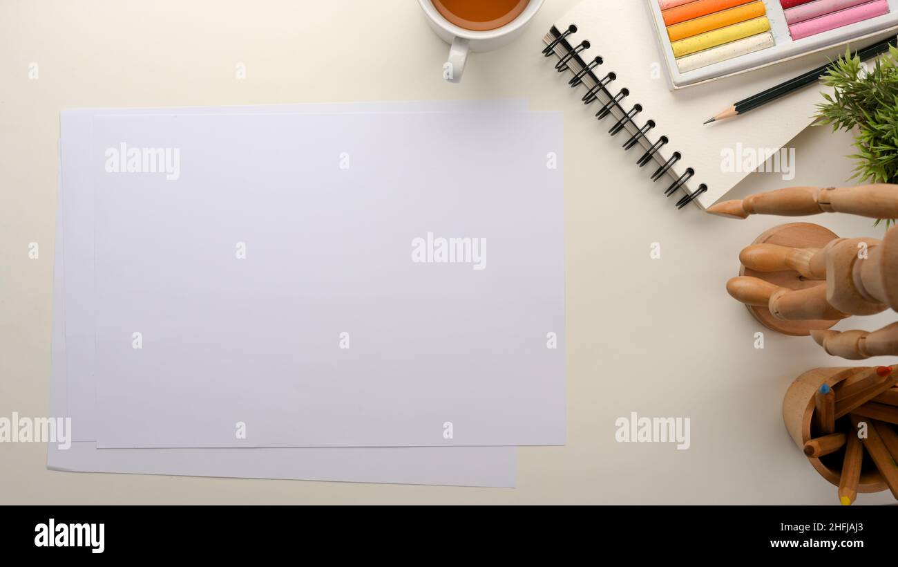 A blank empty paper page on workspace with stationery, oil pastel set ...