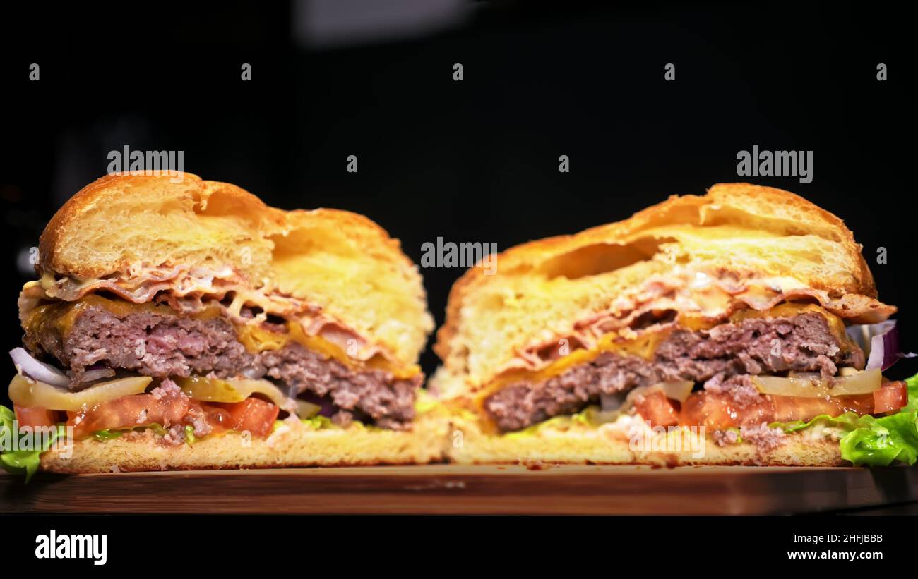 Cut craft burger is cooking on black background. Consist: sauce ...