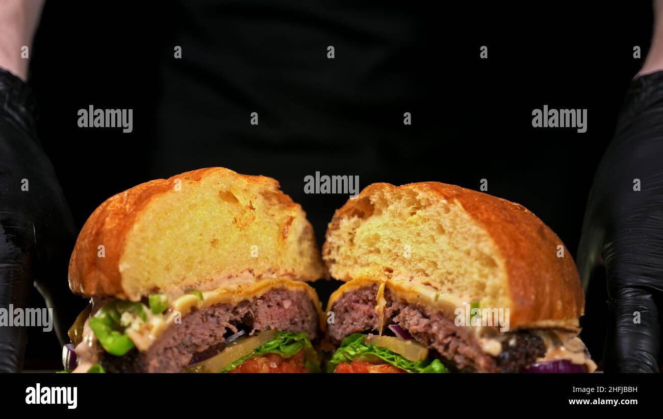 Cut craft burger is cooking on black background. Consist sauce salsa ...