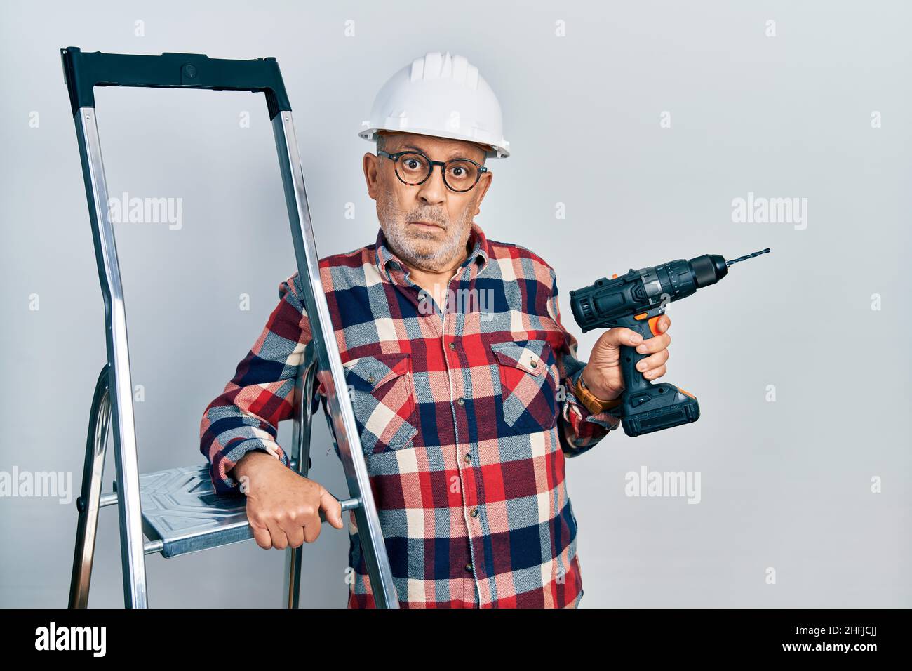 Handsome mature handyman holding screwdriver wearing hardhat by ...