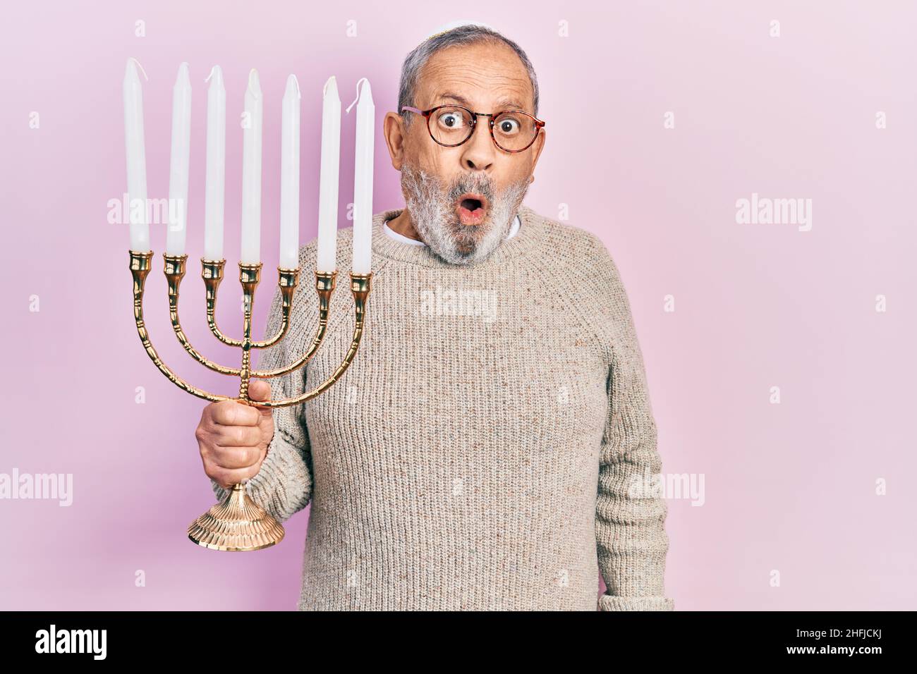 Handsome senior man with beard holding menorah hanukkah jewish candle ...