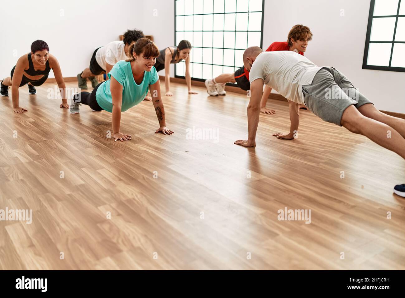Group of young people smiling happy training push-up pectoral exercise ...