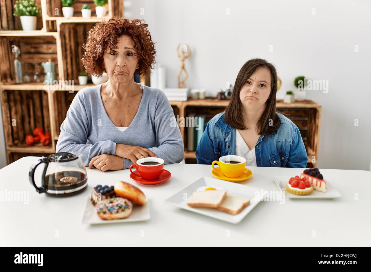 Family of mother and down syndrome daughter sitting at home eating ...