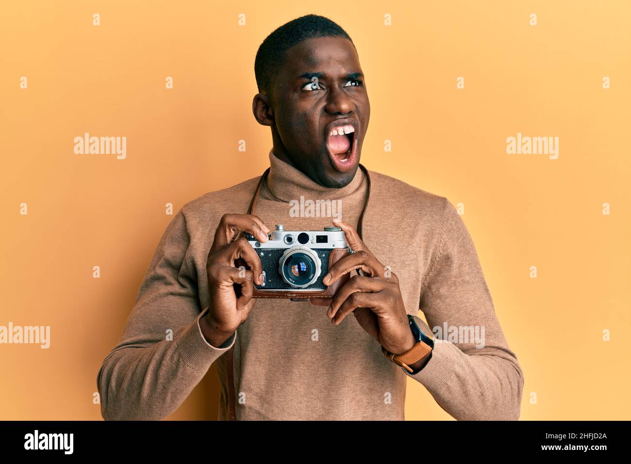 Young african american man holding vintage camera angry and mad ...