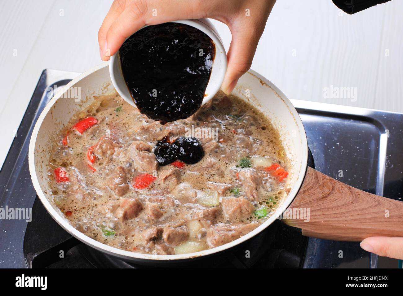 Asian Female Hand Pour Black Pepper Soy Paste To The Pan With Braised