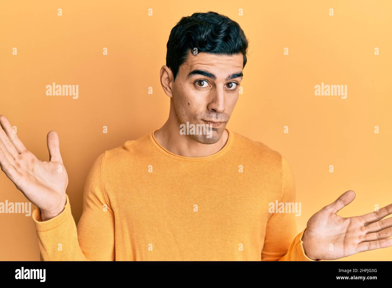 Handsome hispanic man wearing casual clothes clueless and confused with ...