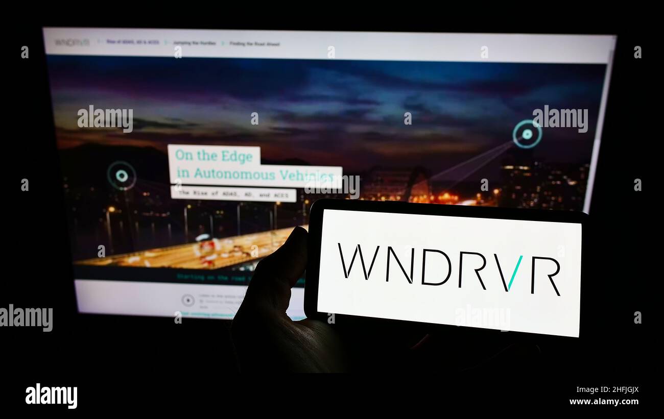 Person holding smartphone with logo of US software company Wind River ...