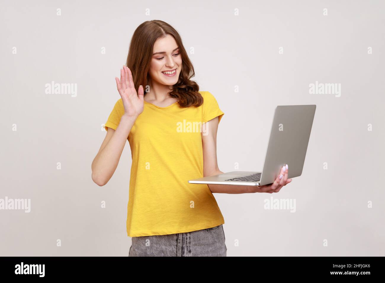Hi. Beautiful teenager girl with wavy hair waving hand, gesturing hello ...