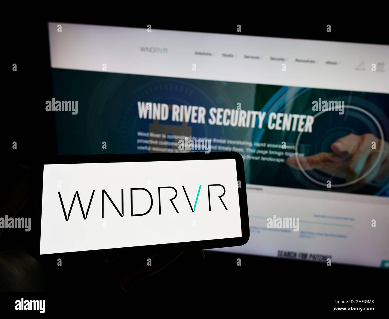 Person holding cellphone with logo of US software company Wind River ...