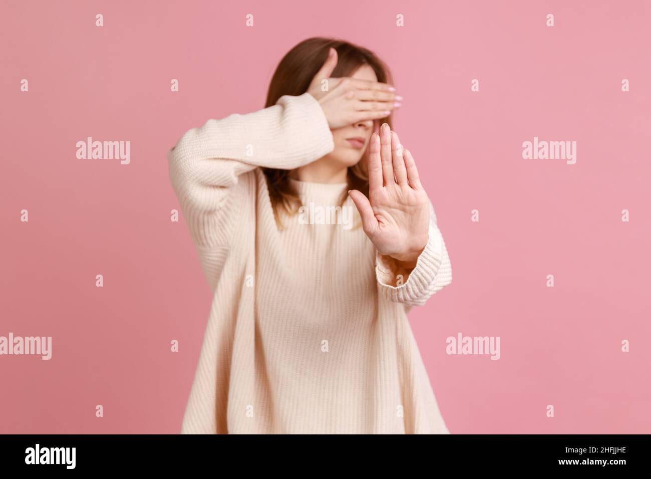 Woman covering eyes with hand showing stop gesture, rejecting to watch ...