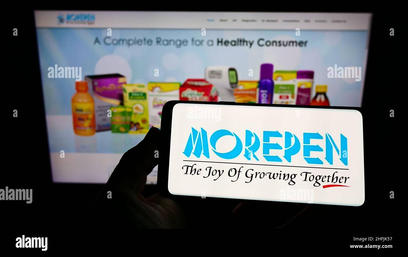 Person holding smartphone with logo of pharmaceutical company Morepen ...