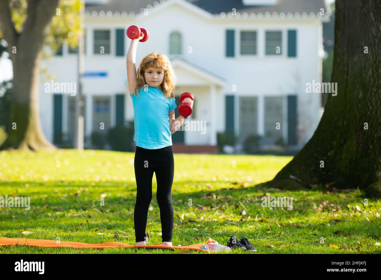 Child boy raising a dumbbell. Cute child training with dumbbells ...