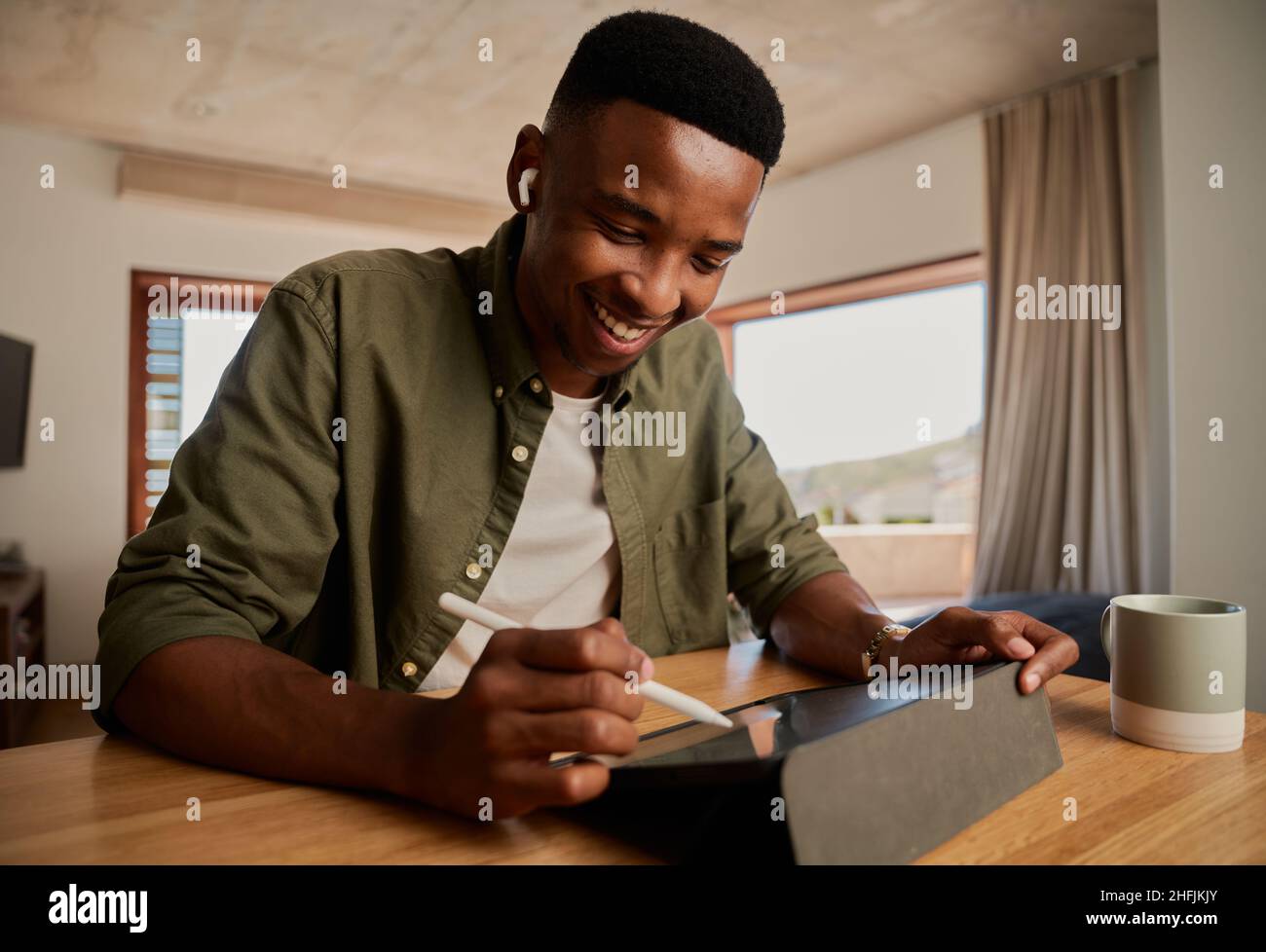 Excited young adult black male writing with pen on electronic tablet ...