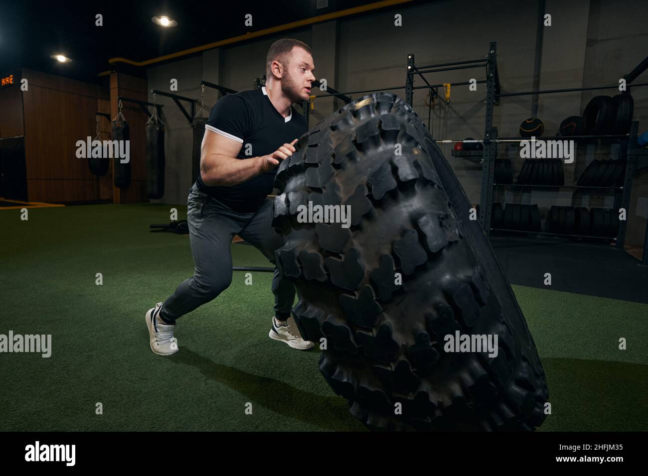 Concentrated sportsman performing tyre exercise at gym Stock Photo - Alamy