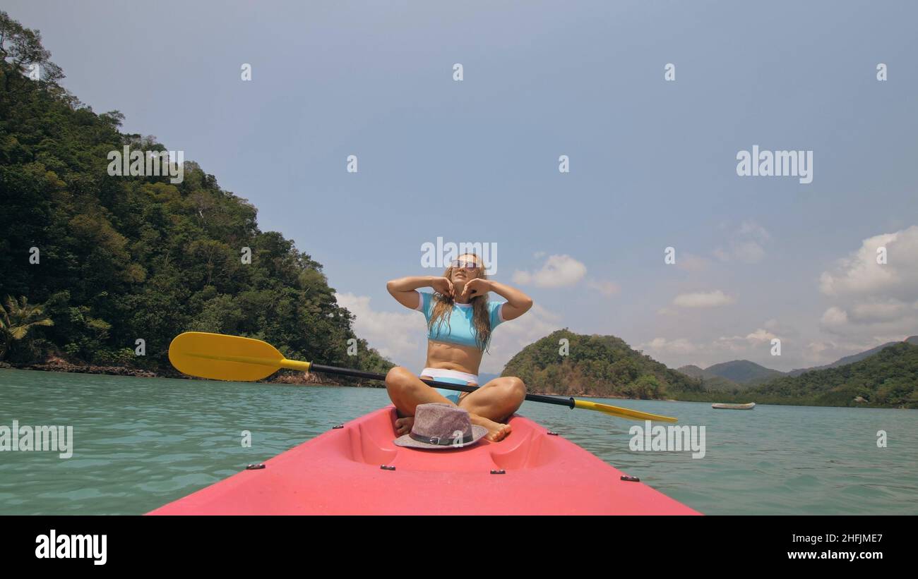 Sportive woman rows pink plastic canoe along sea water. Positive sports ...