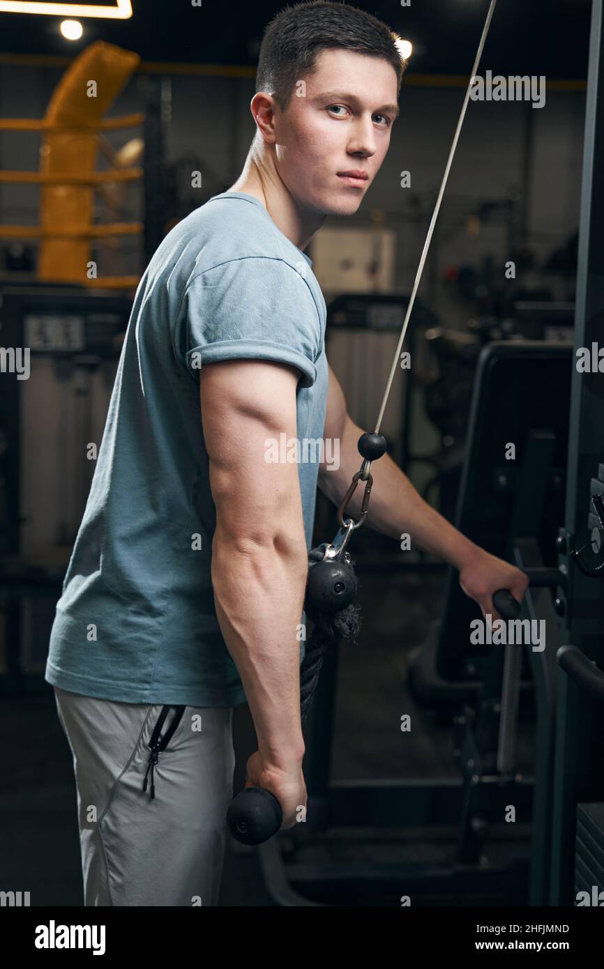 Tranquil athletic man performing standing single-arm tricep pushdown ...