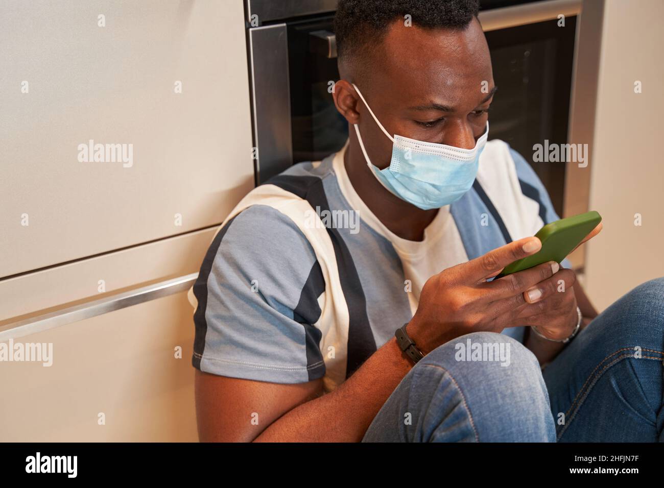 Man staring at phone display while sitting in kitchen Stock Photo - Alamy