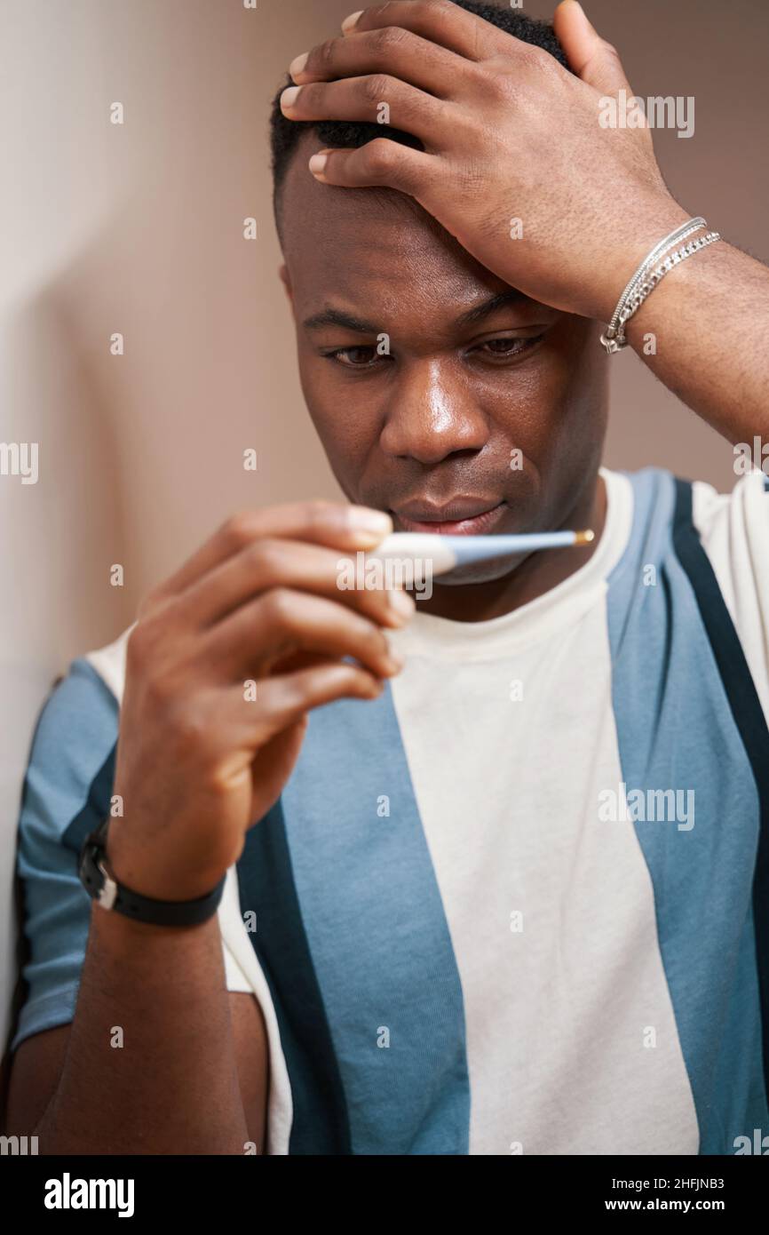 Shocked man staring at his temperature values on thermometer Stock ...