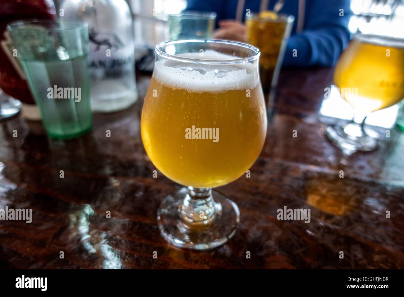 View of a frothy, ice cold farmhouse ale on a wooden table inside a ...