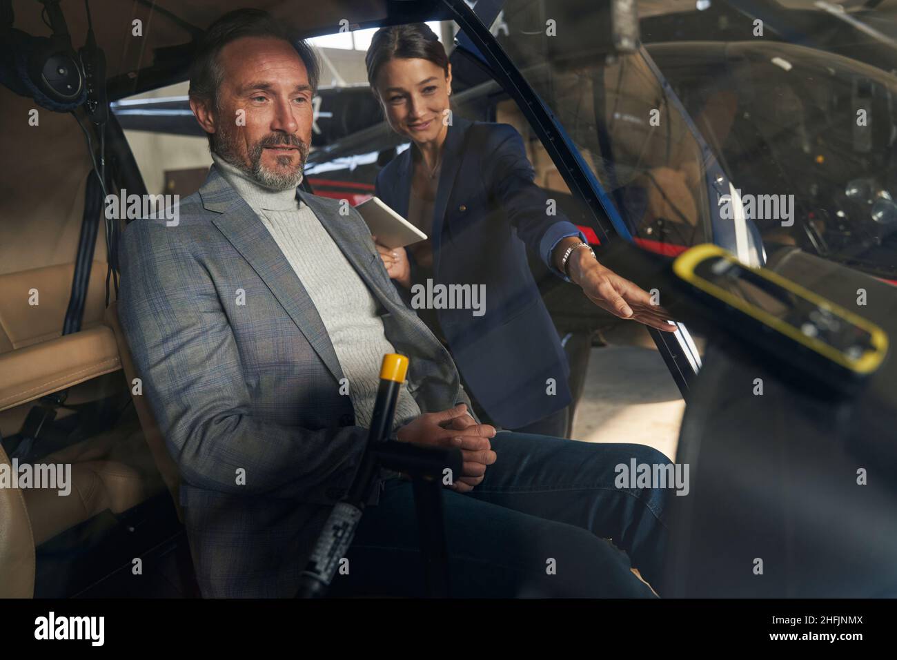 Aircraft hangar manager demonstrating helicopter cockpit to customer ...
