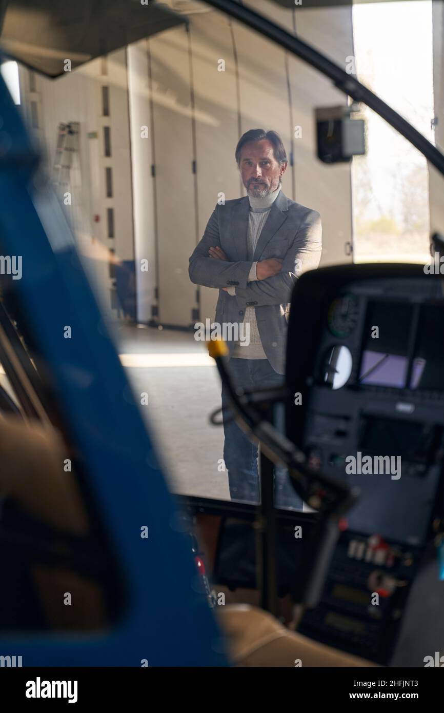 Tranquil mature gentleman looking at hangared helicopter Stock Photo ...