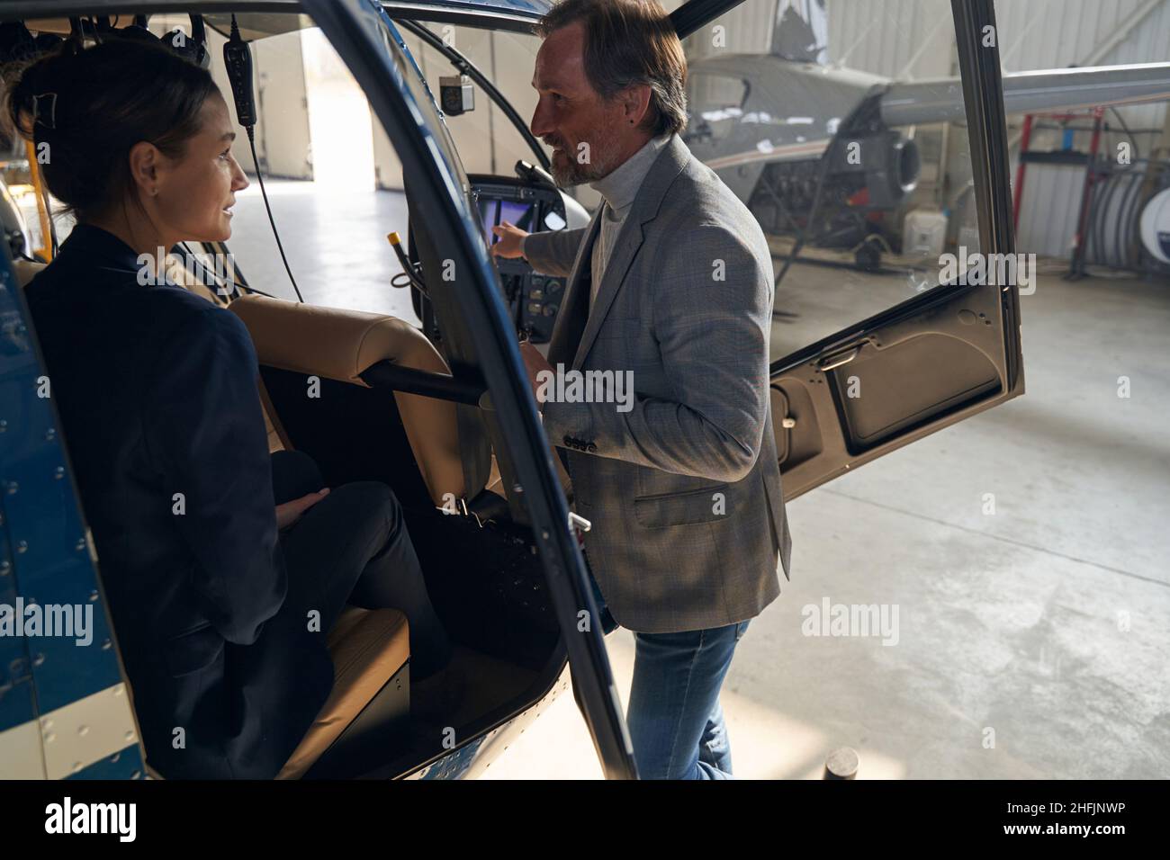 Passenger seated in hangared helicopter being instructed by private ...