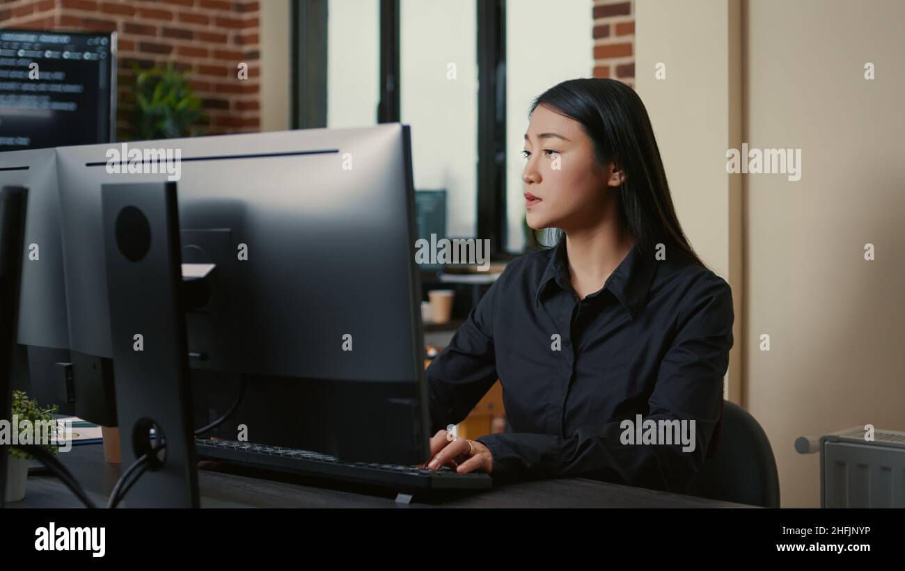 Portrait of asian programer focused on writing code sitting at desk in software development ...