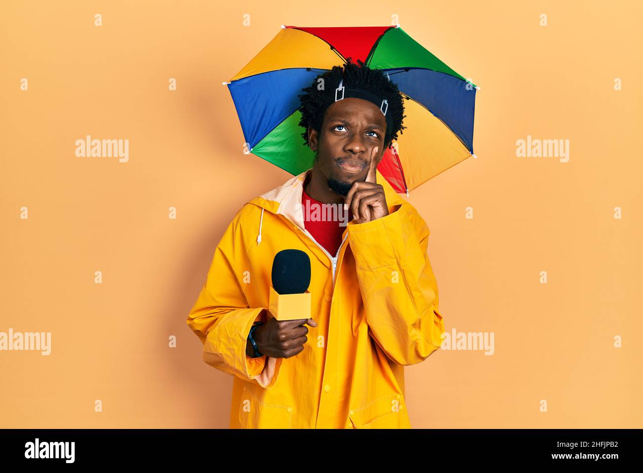 Young african american journalist man wearing yellow raincoat and ...