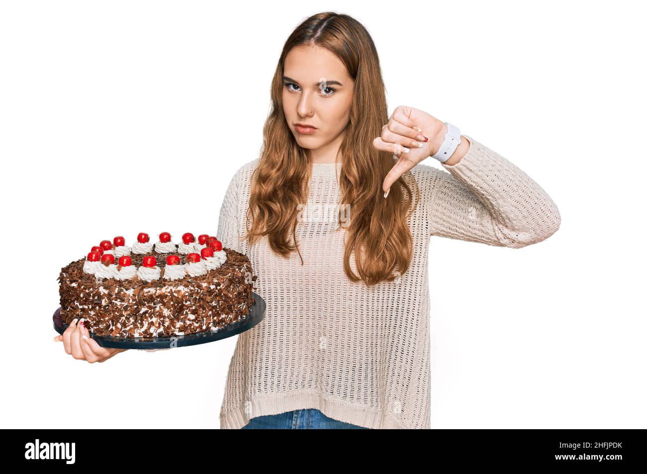 Young blonde woman celebrating birthday holding big chocolate cake with ...