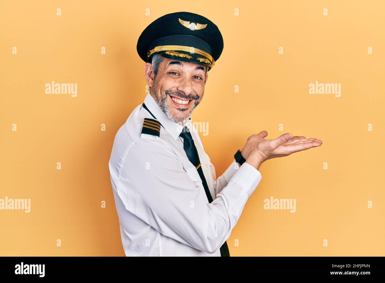Handsome middle age man with grey hair wearing airplane pilot uniform ...