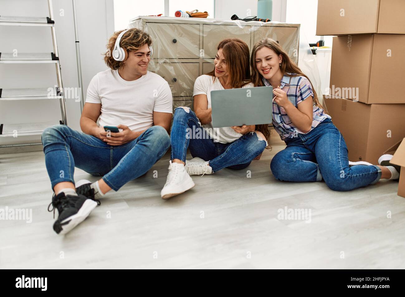 Mother and couple using smartphone and laptop sitting on the floor at ...