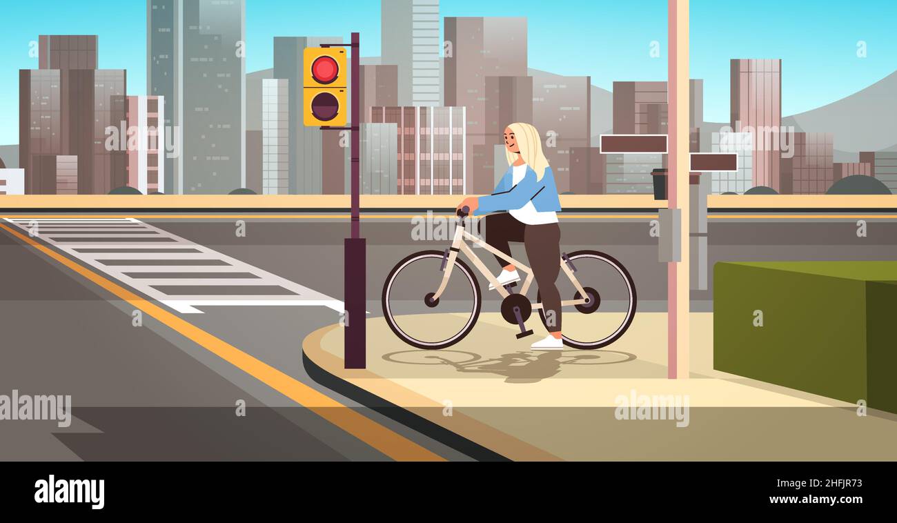 young woman cyclist waiting for green traffic light to cross road on ...