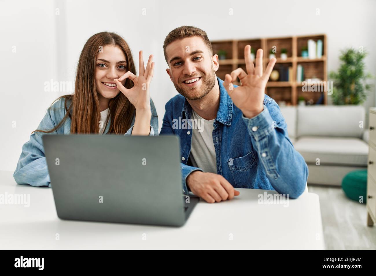 Young caucasian couple working using computer laptop at home doing ok ...