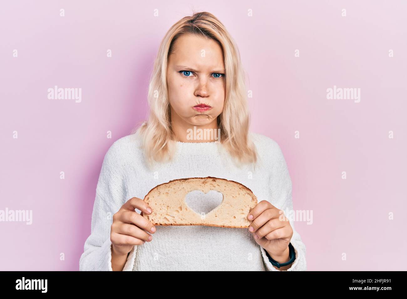 Beautiful caucasian blonde woman holding bread loaf with heart shape ...