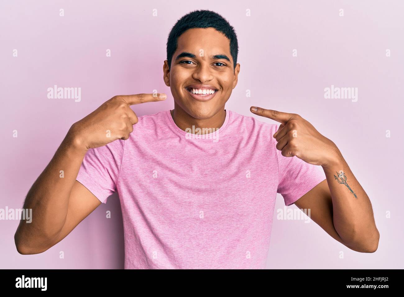 Young handsome hispanic man wearing casual pink t shirt smiling ...