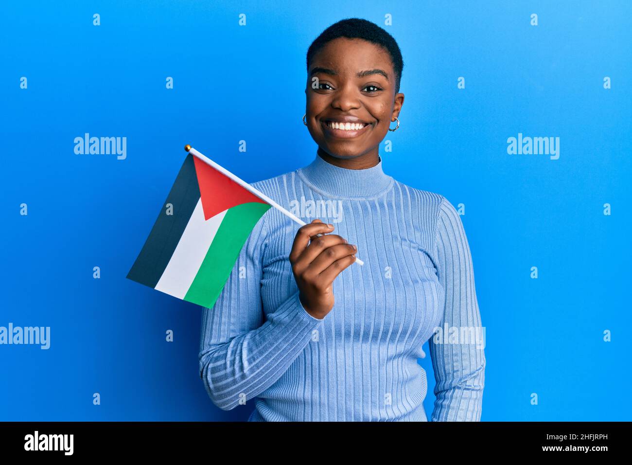 Young african american woman holding palestine flag looking positive ...