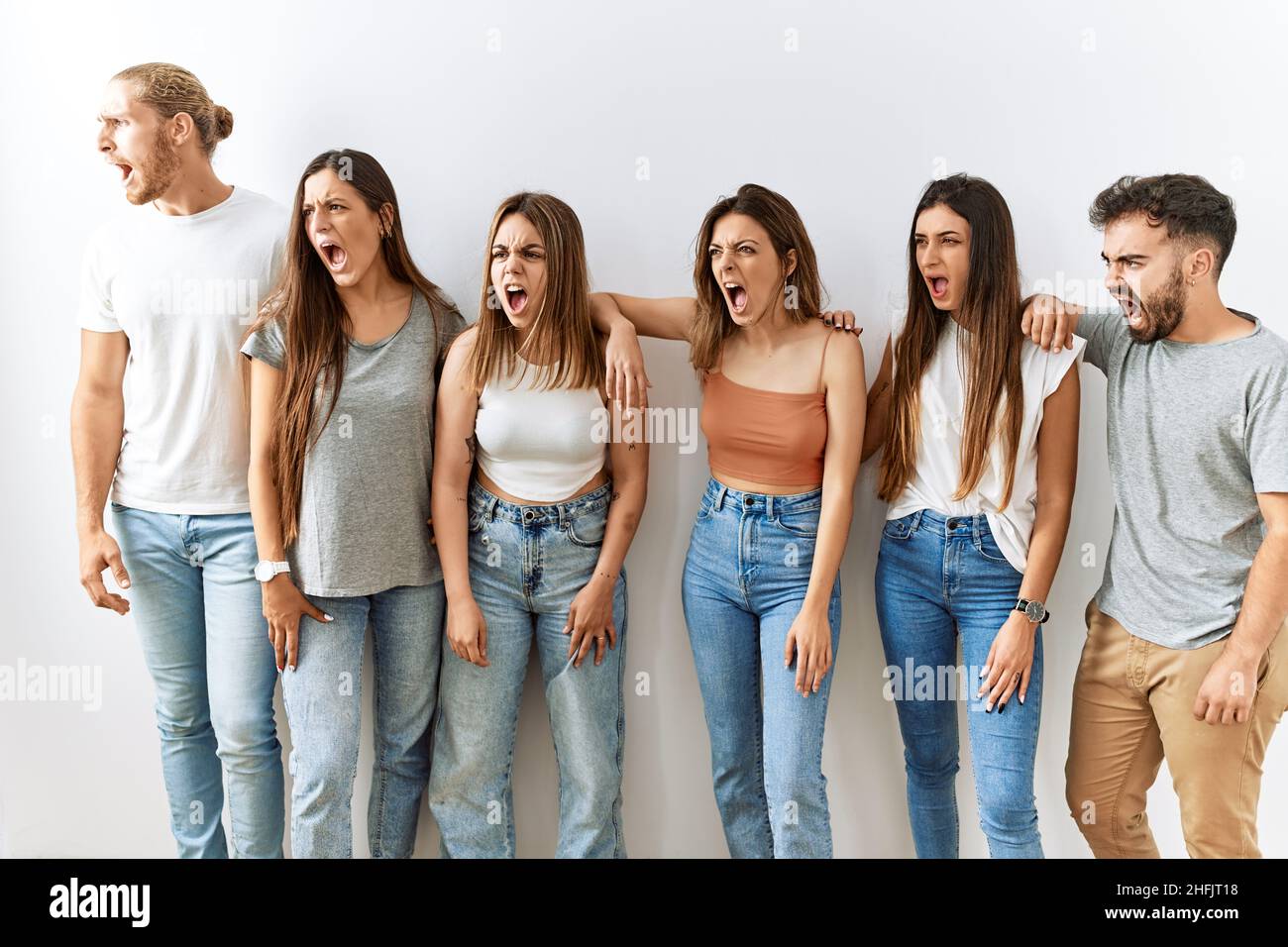 Group of young friends standing together over isolated background angry ...