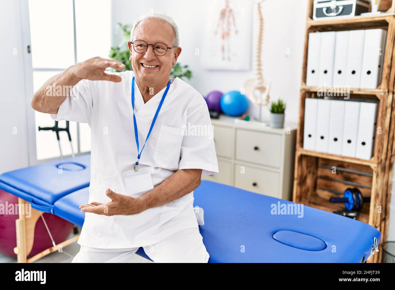 Senior physiotherapy man working at pain recovery clinic gesturing with ...