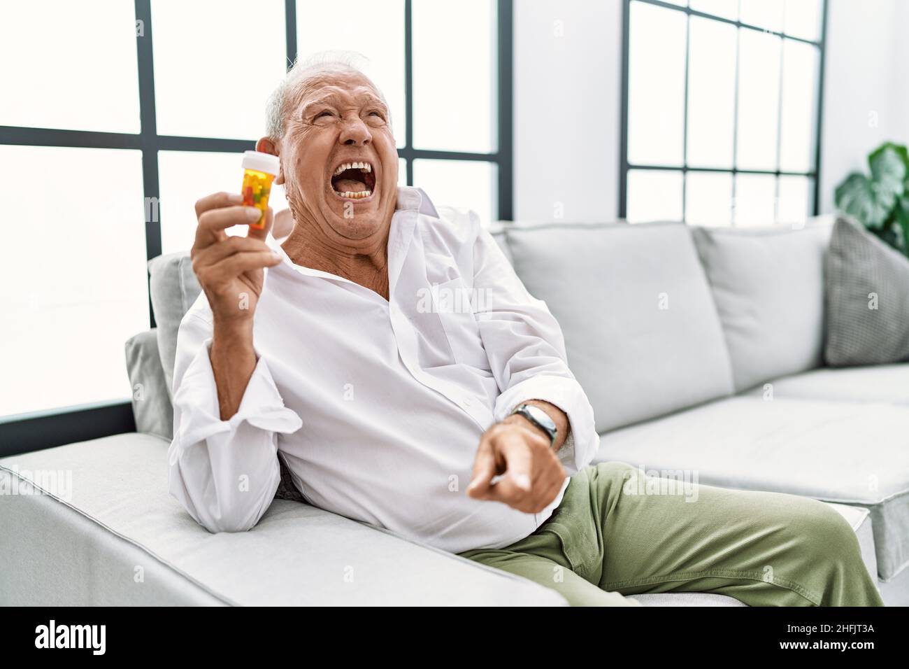 Senior man holding pills angry and mad screaming frustrated and furious ...