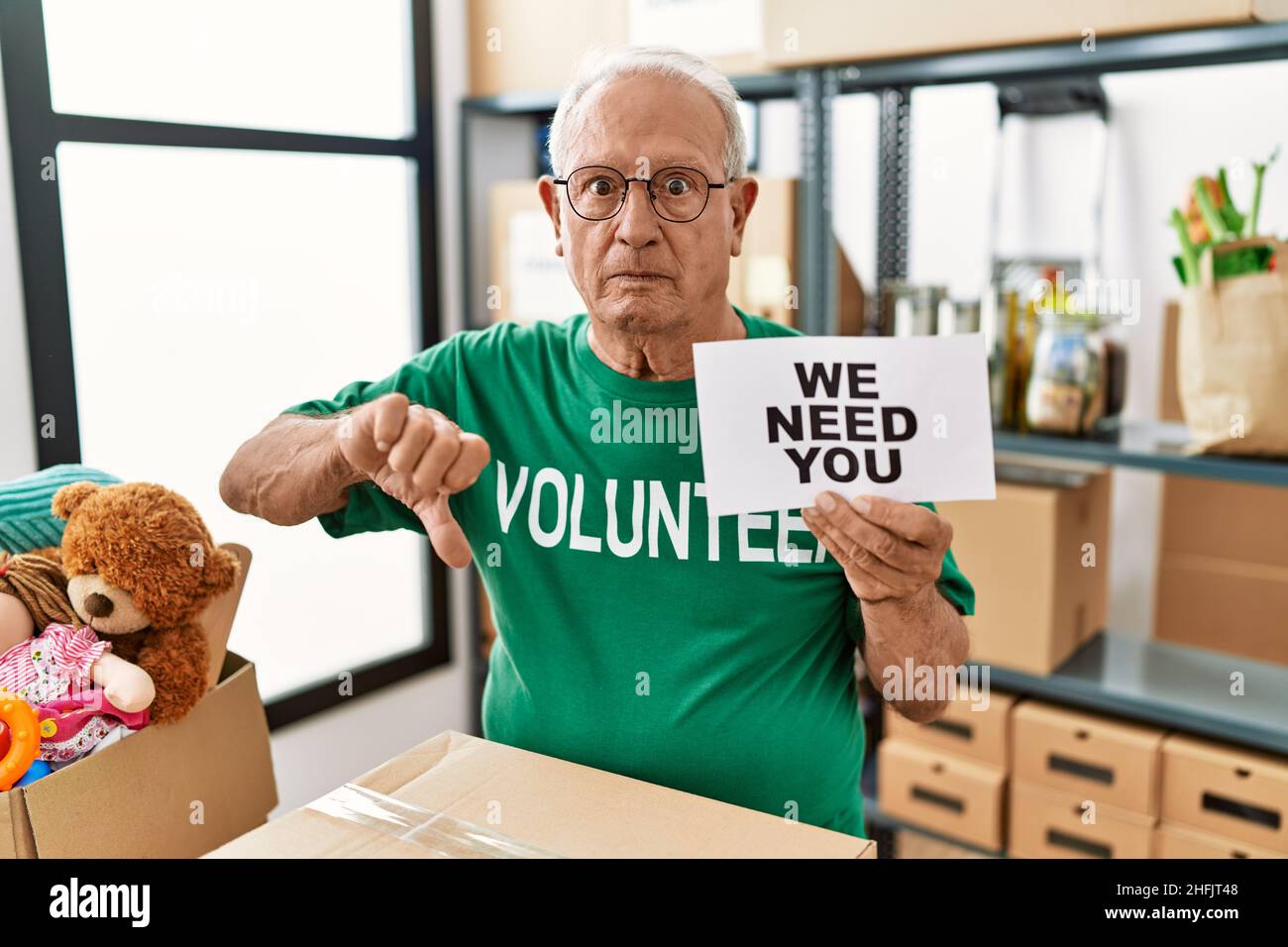 Senior volunteer man holding we need you banner with angry face ...