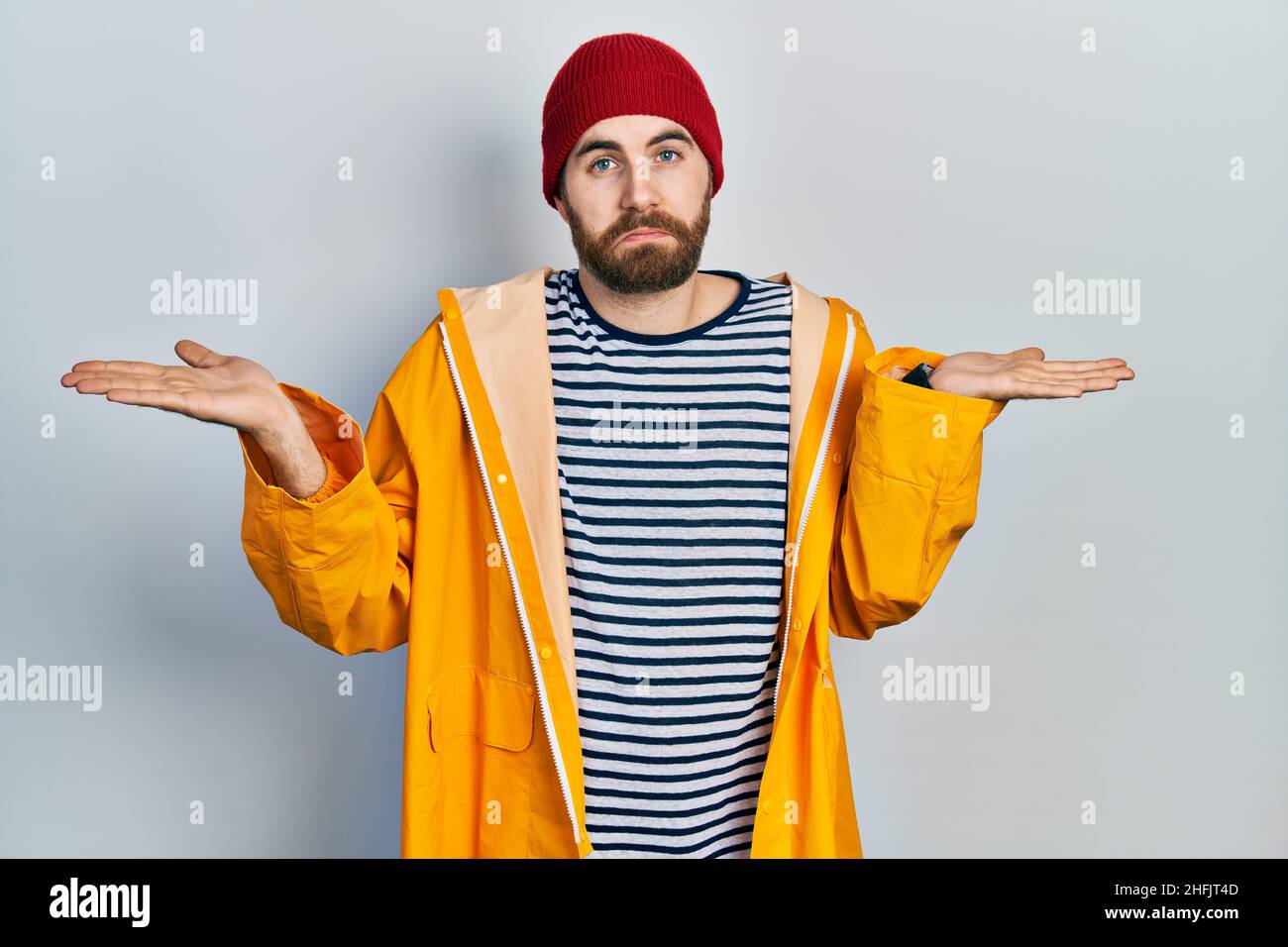 Caucasian man with beard wearing yellow raincoat clueless and confused ...