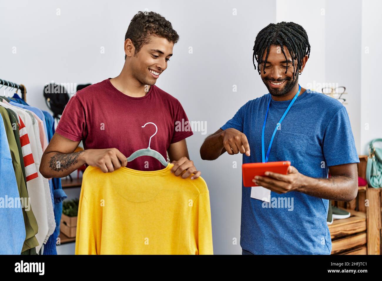 Two men asking shopkeeper for clothes size using touchpad at clothing ...