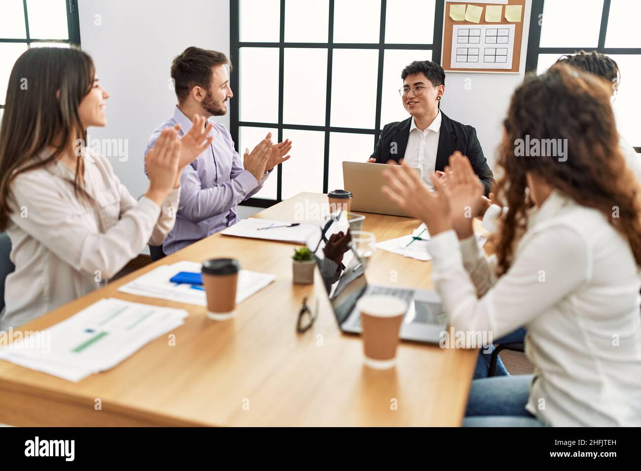 Group of business workers smiling and clapping to partner at the office ...