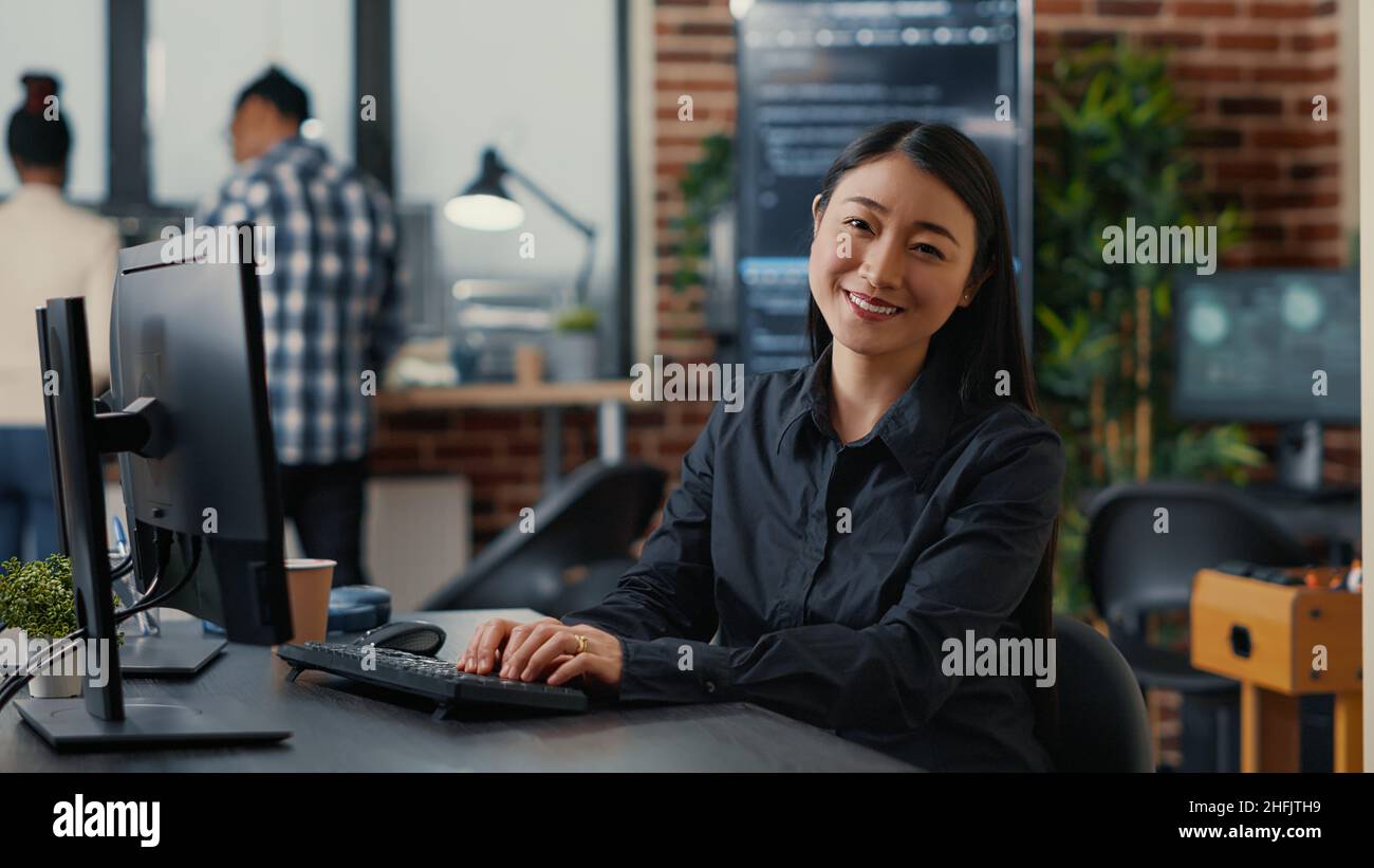 Smiling Asian Database Software Developer Writing Programming Code On Computer Keyboard Sitting