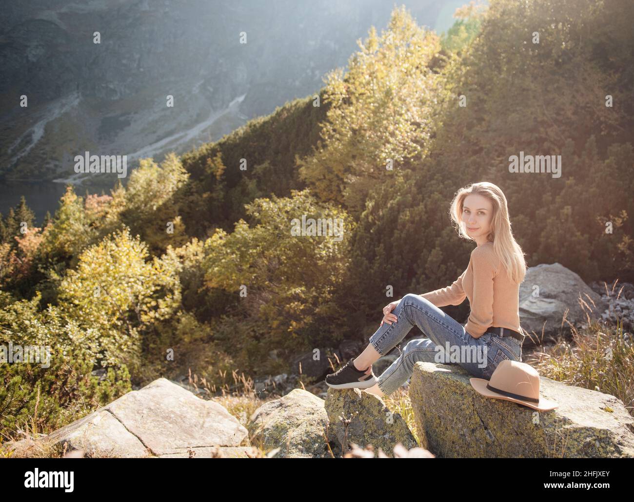 Young woman tourist sitting on the mountain peak and beautiful ...