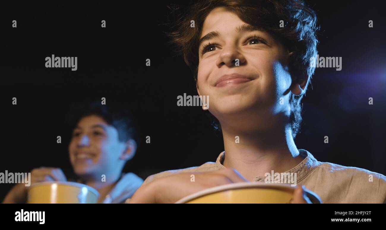Boy watching a comedy movie at the cinema, he is eating popcorn and ...