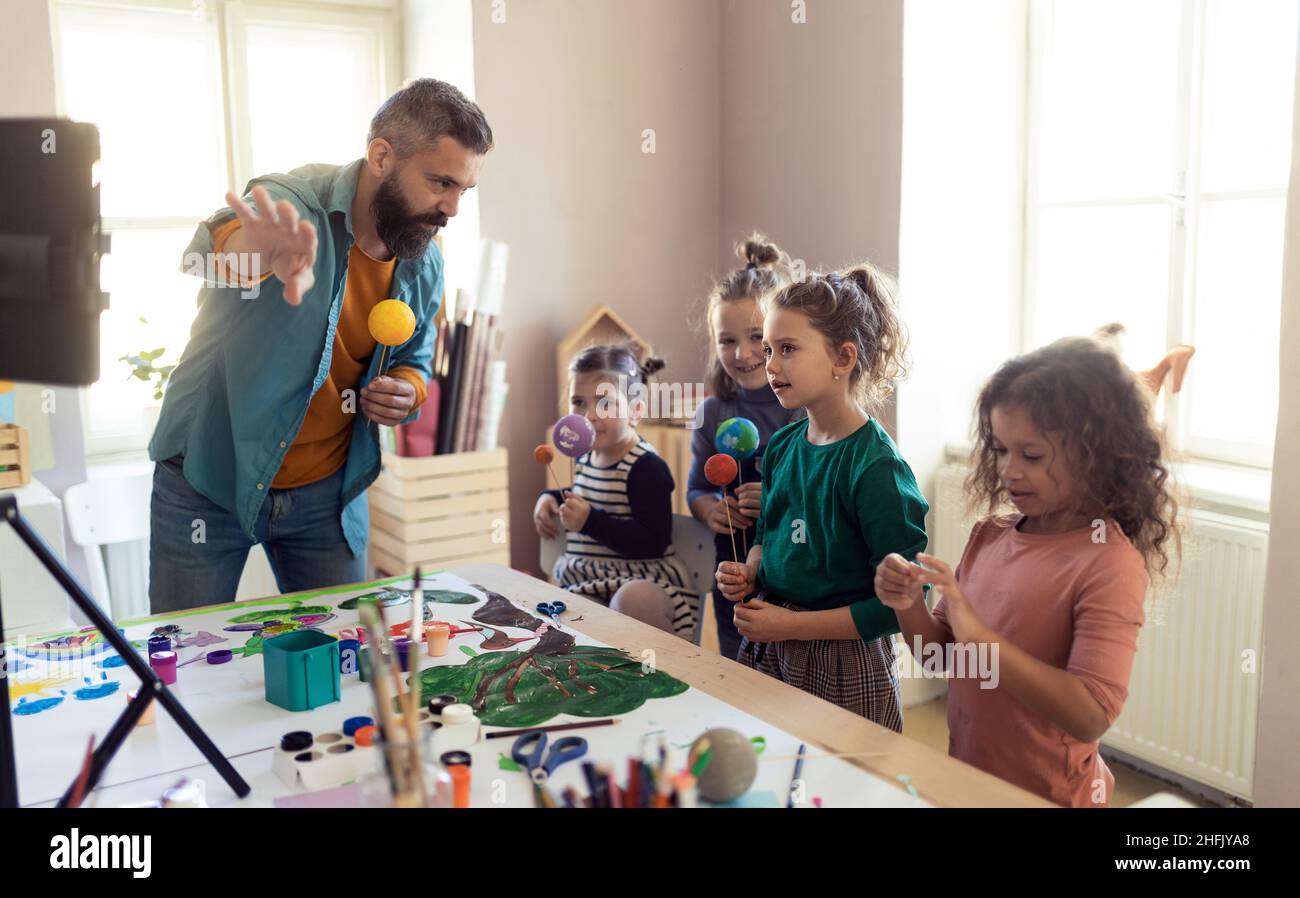 Group of little kids working on project with teacher during creative ...