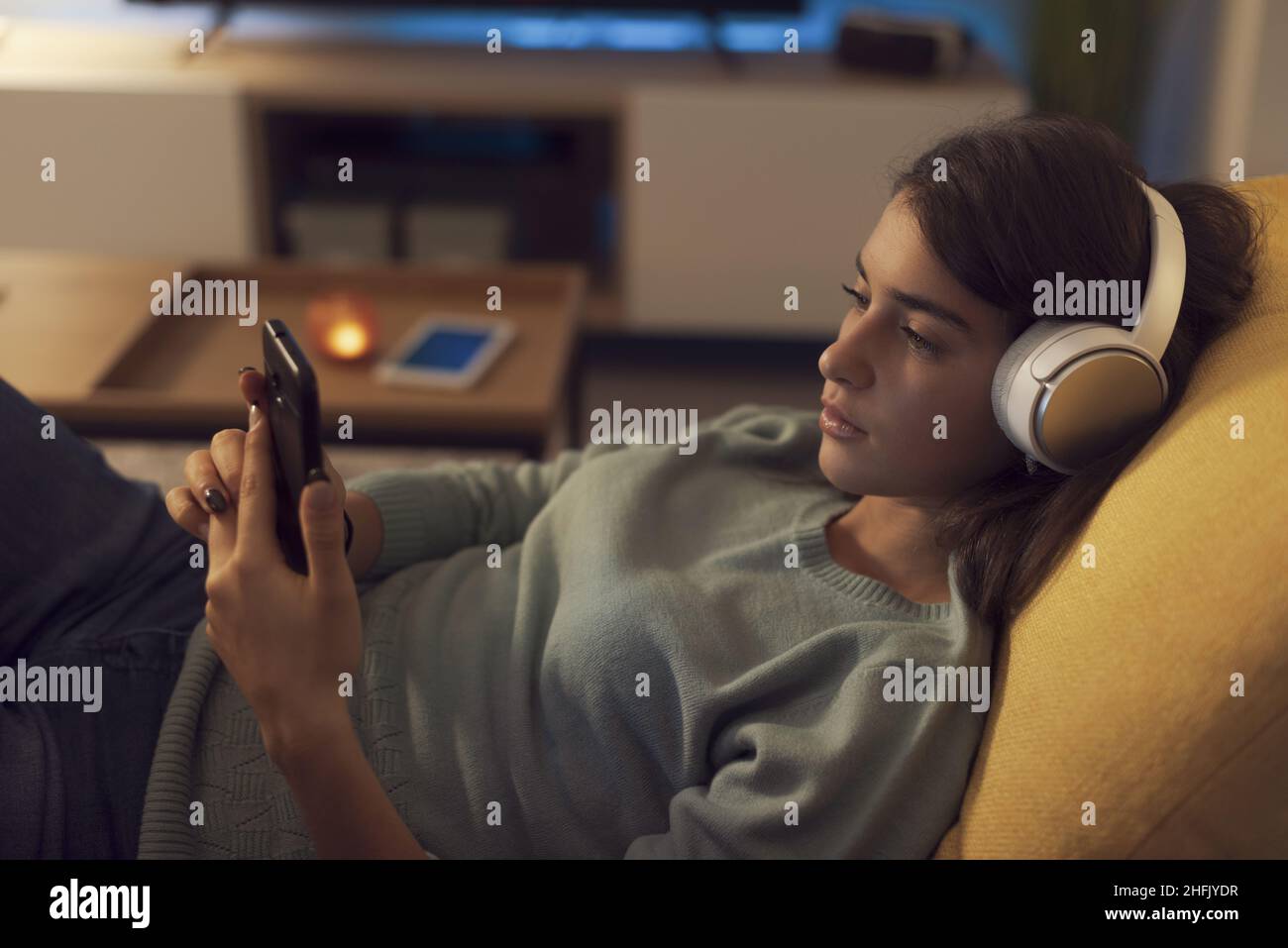 Young woman lying down on the couch and relaxing, she is wearing ...
